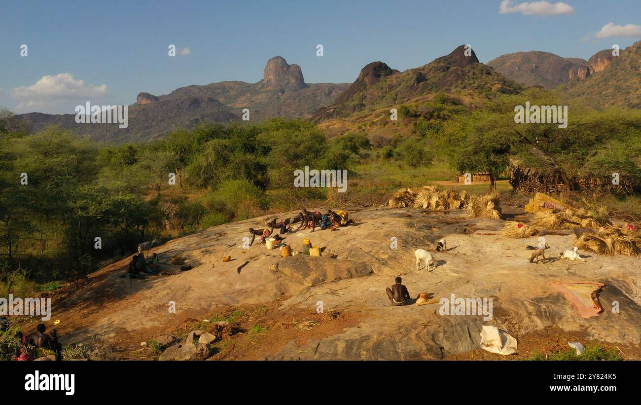 Larim tribe women grinding sorghum grains in holes in a rock, Boya ...