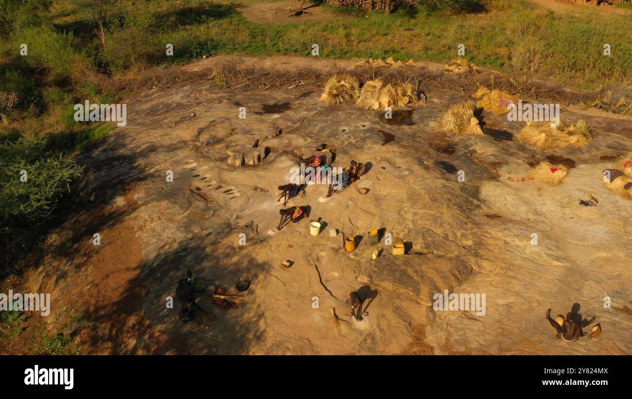 Larim tribe women grinding sorghum grains in holes in a rock, Boya ...