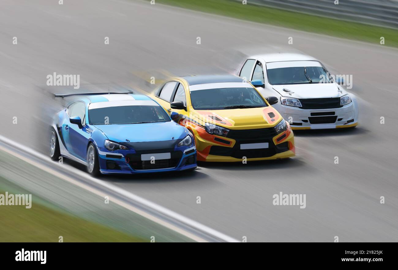 Three race cars racing at high speed on speed track with motion blur on ...