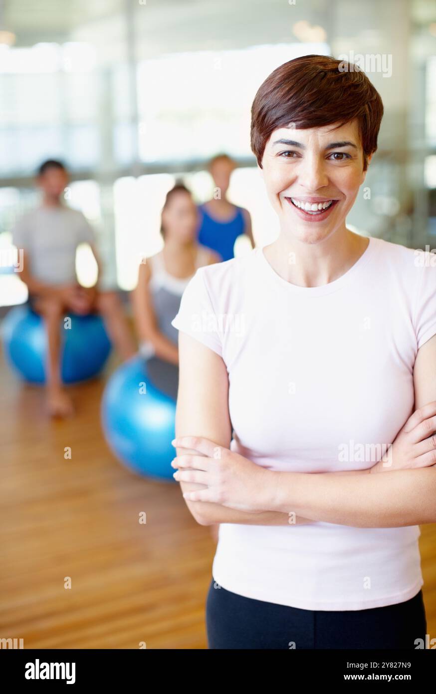 Woman, portrait and trainer with arms crossed in yoga class for ball ...