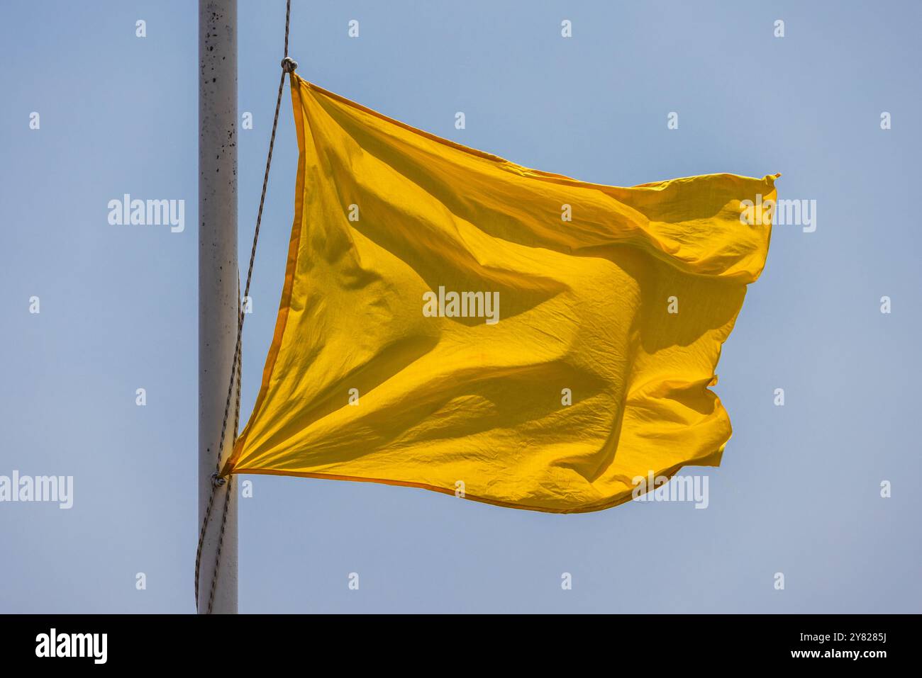 Yellow warning flag mounted on a beach lifeguard station is waving on ...