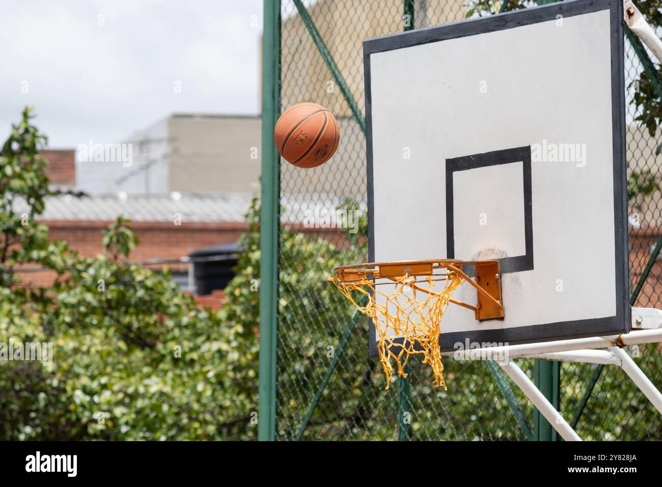 orange ball of basketball near to white backboard and hoop in a street ...