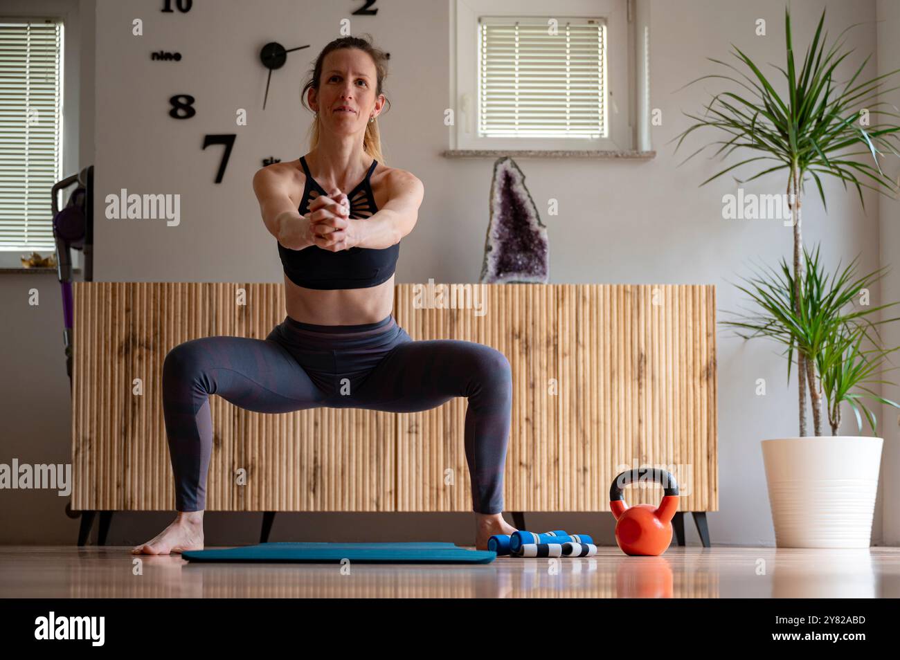 Fit young woman in sportswear exercising at home on a yoga mat. Doing a ...