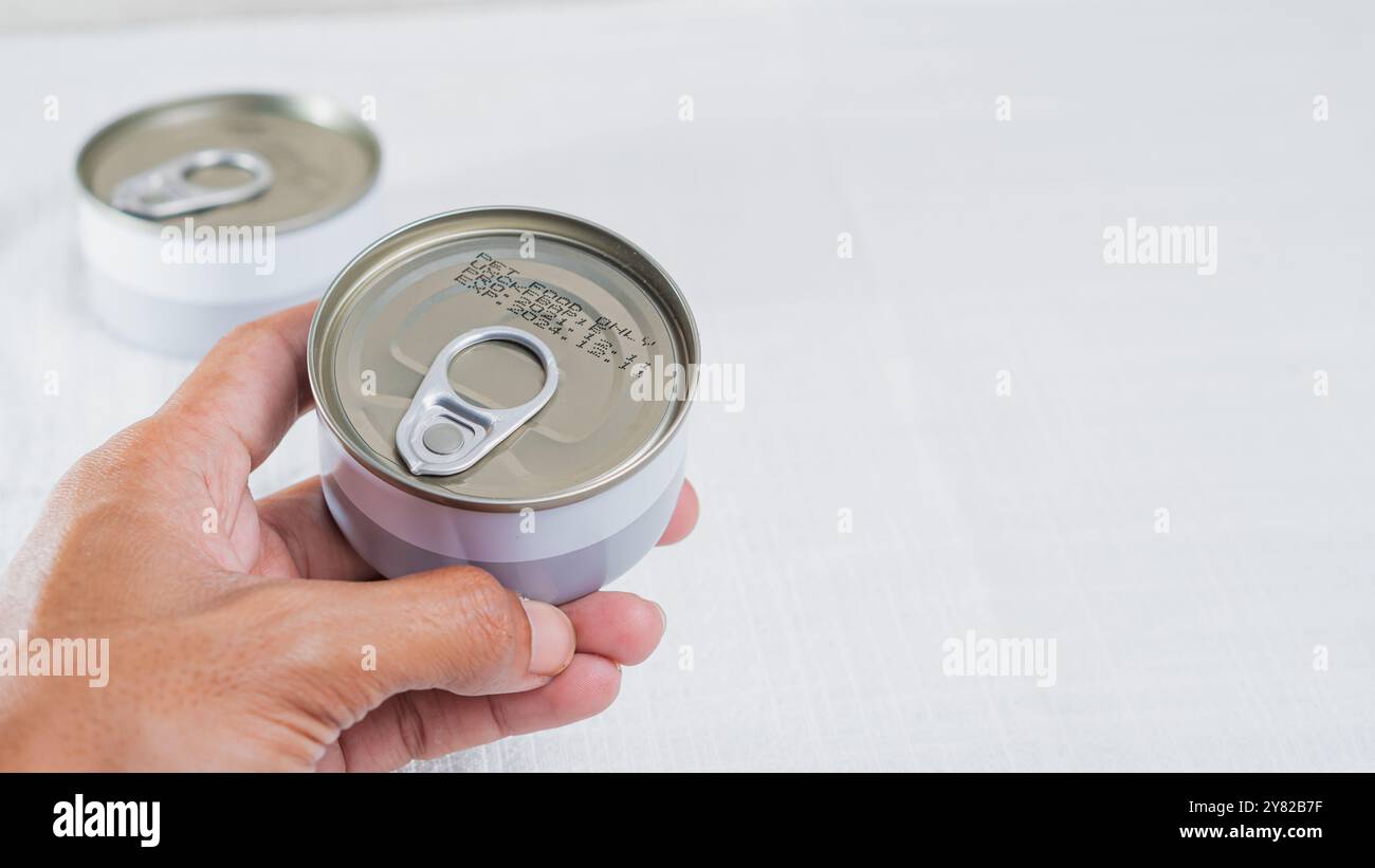 A person holding a can with a pull-tab lid, showing the bottom of the ...