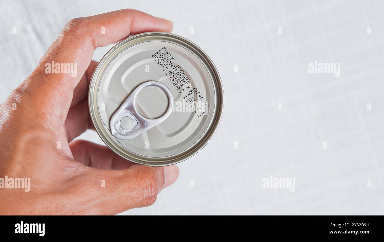 A hand holding a can with a pull tab, showing the top view of the can ...