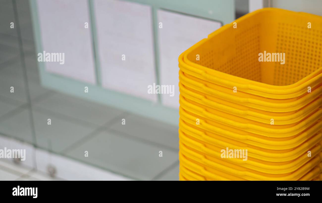 A stack of bright yellow plastic baskets arranged neatly. The ...