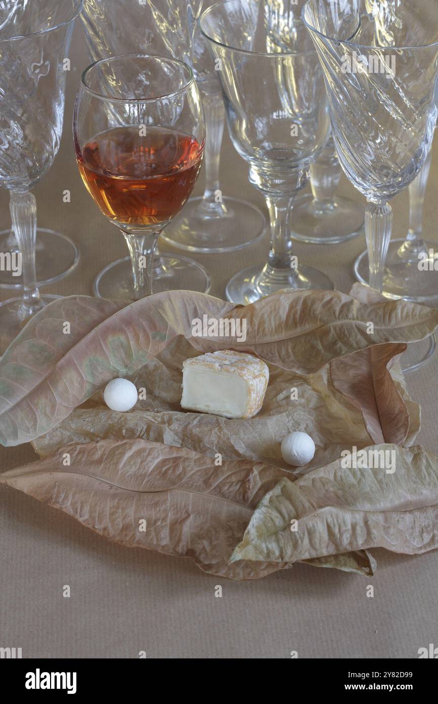 Camembert cheese piece, surrounded by empty wine glasses, one with red ...