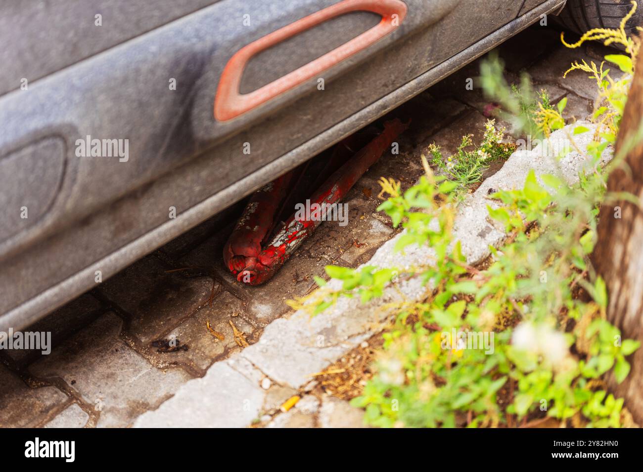 The rumpled destroyed red orange road plastic column under the car ...