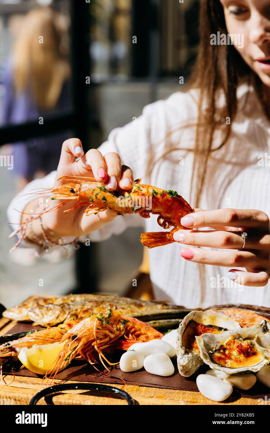 Young woman peeling shrimp at seafood restaurant, perfect for food ...