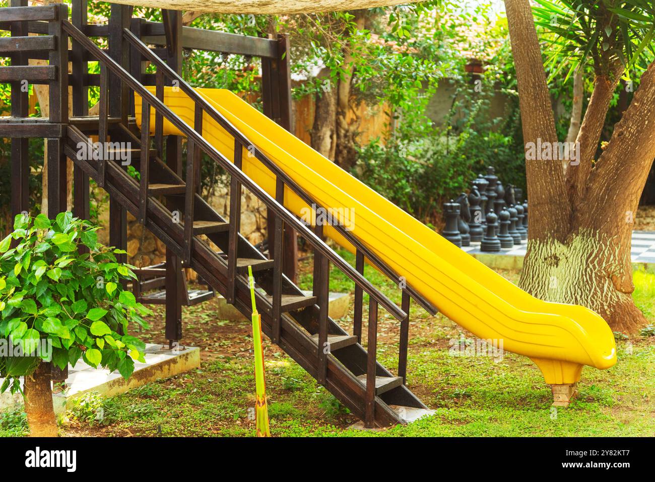 A bright yellow slide with stairs in a wellkept park area Stock Photo ...