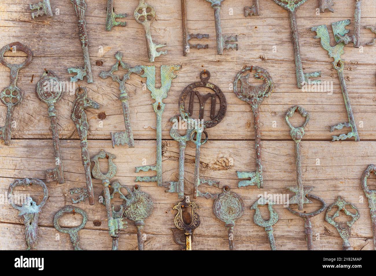 A collection of old and rusted keys are hanging on a wooden wall Stock ...