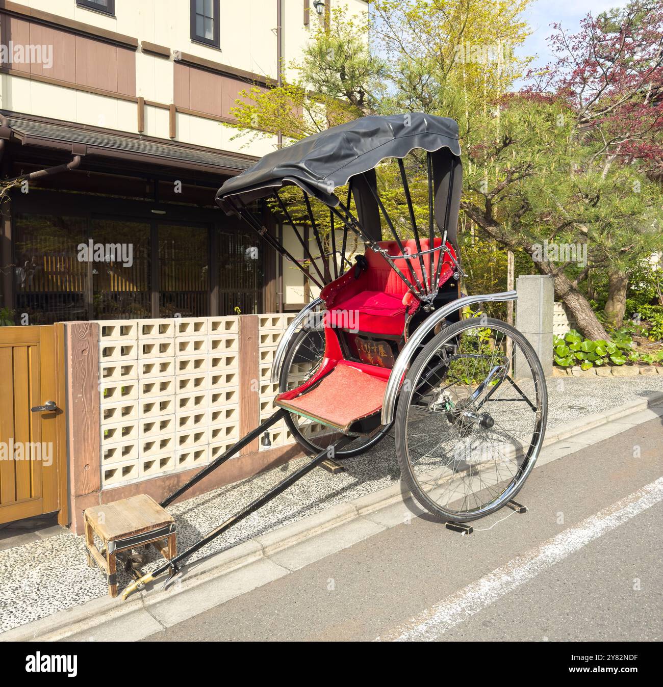 Traditional red hand pulled Indian rickshaw parked on the roadside ...
