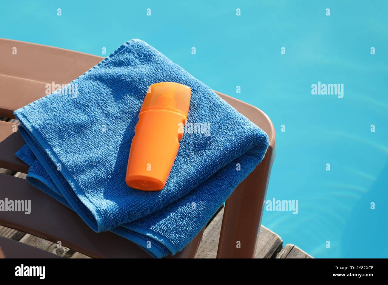 Towel and sunscreen on sun lounger near outdoor swimming pool Stock ...