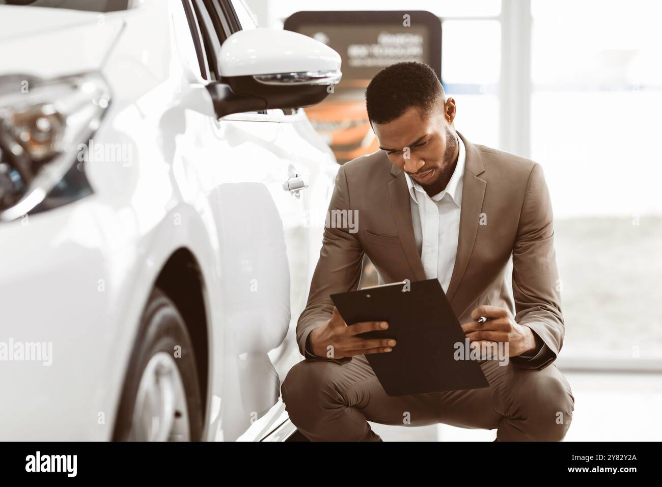Auto Insurance Agent Sitting Taking Notes Working In Dealership Center ...