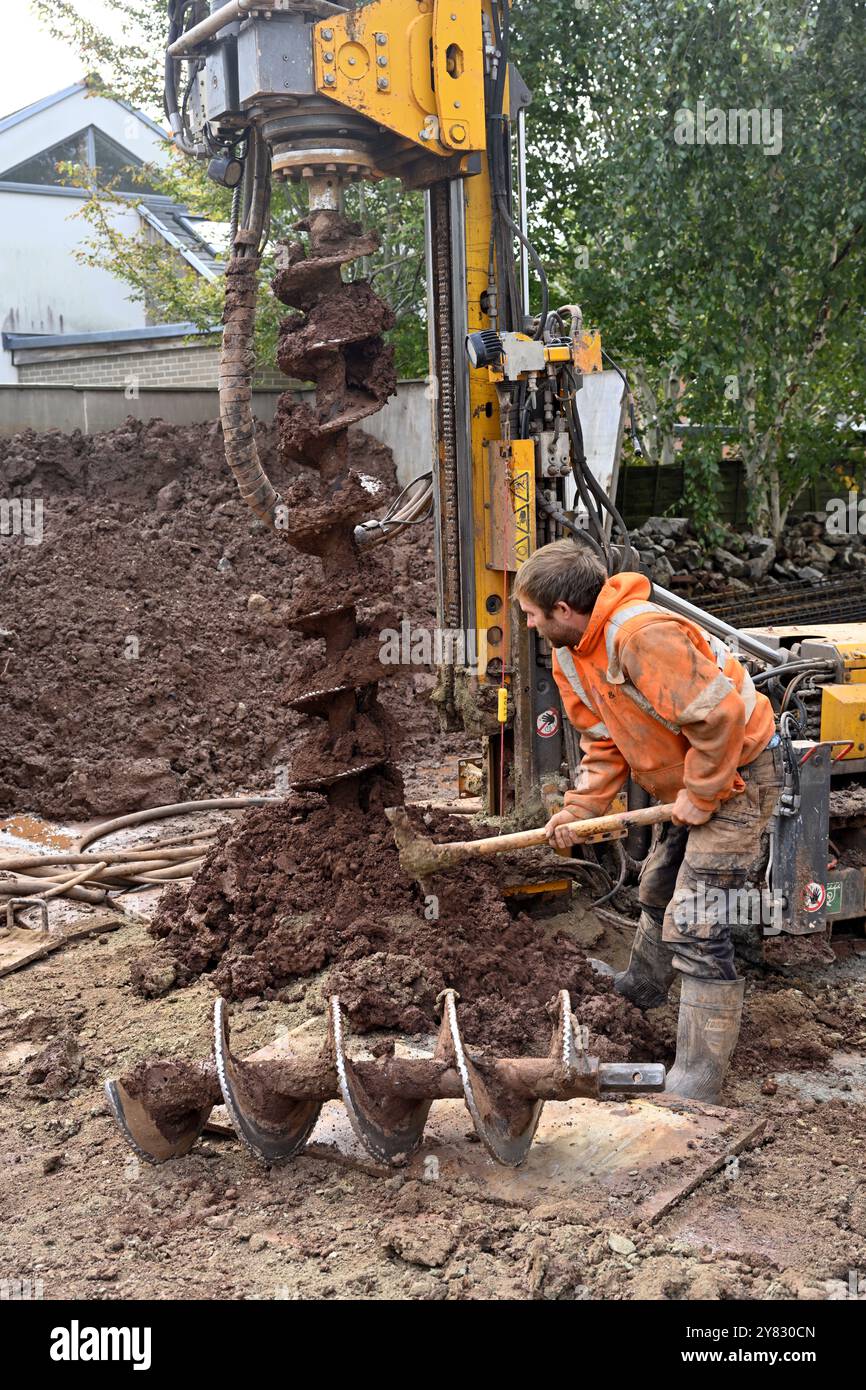 Manually clearing of spoils from auger pile drilling machine drilling ...