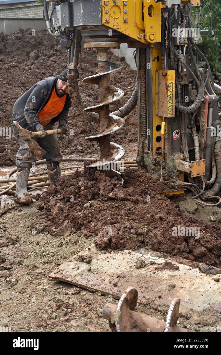 Manually clearing of spoils from auger pile drilling machine drilling ...