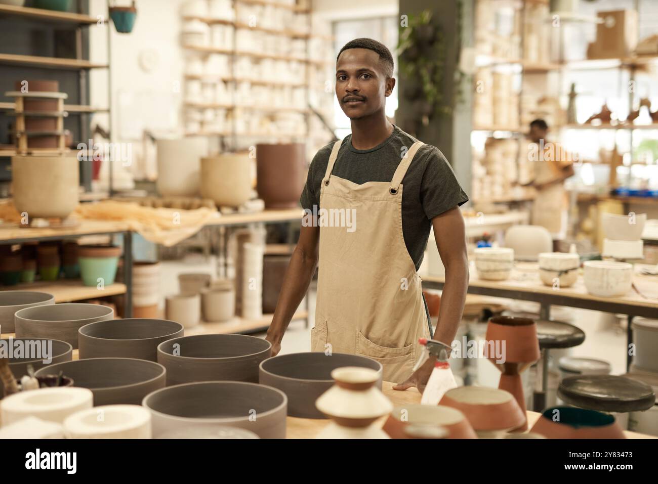 Portrait of a young African ceramics studio worker wearing an apron ...