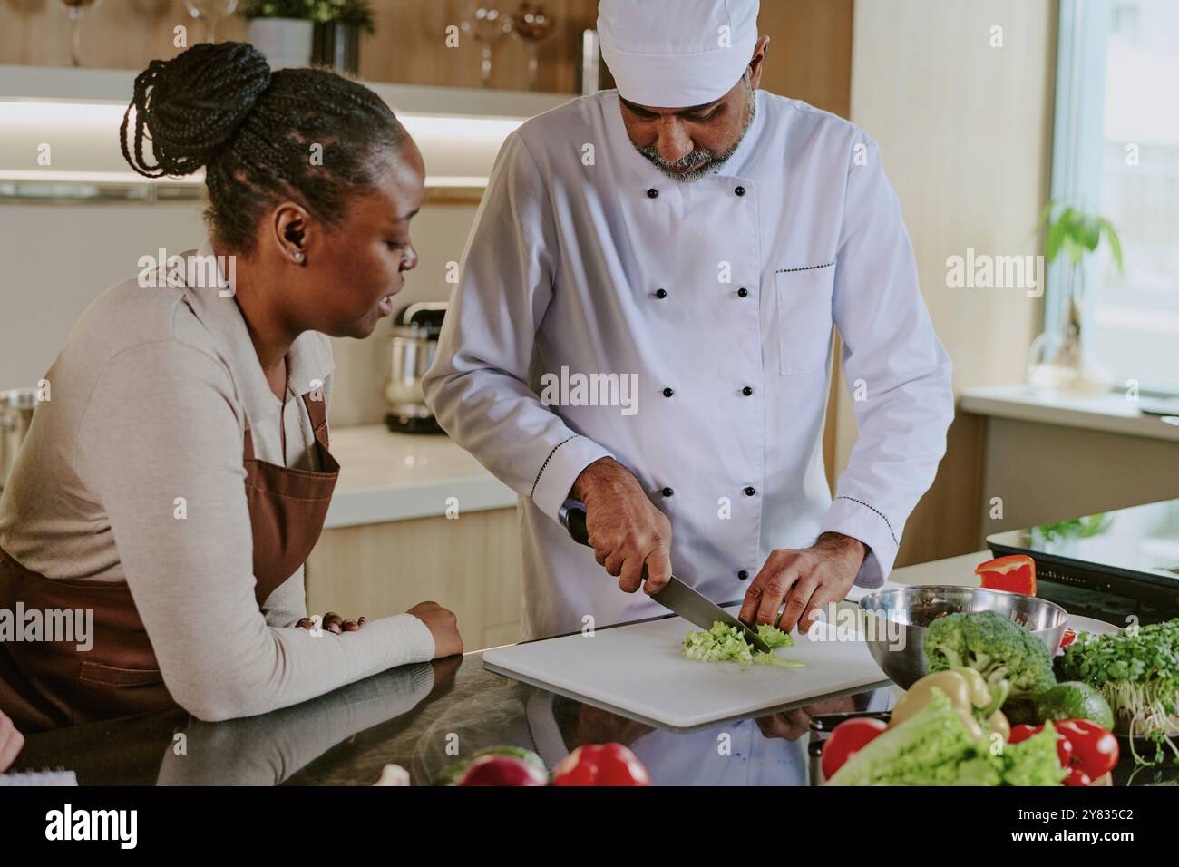 African American female intern watching professional Indian chef ...