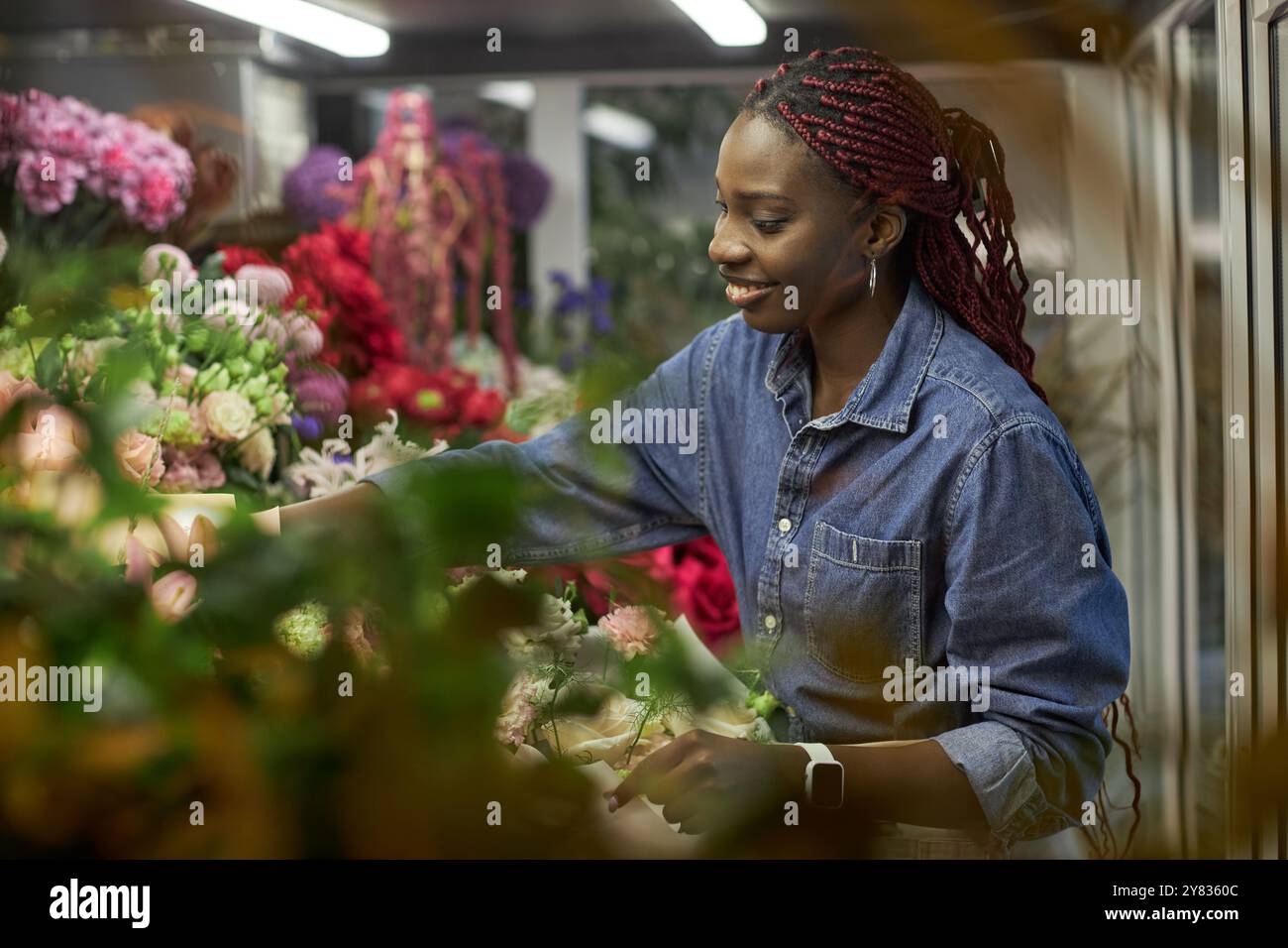 Side view portrait of smiling Black woman caring for beautiful flowers ...