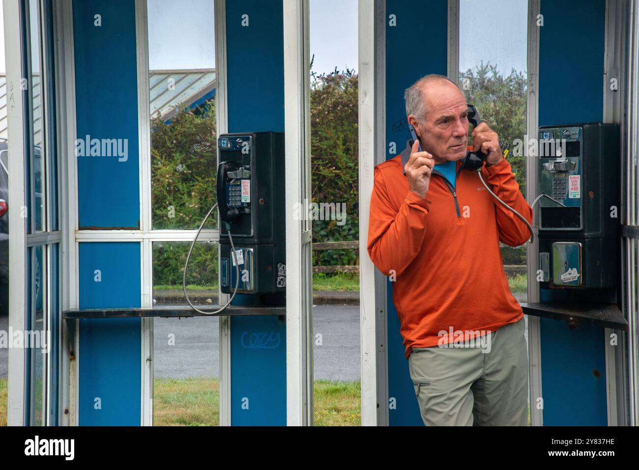 A single senior male uses a cell phone and a landline at the same time ...