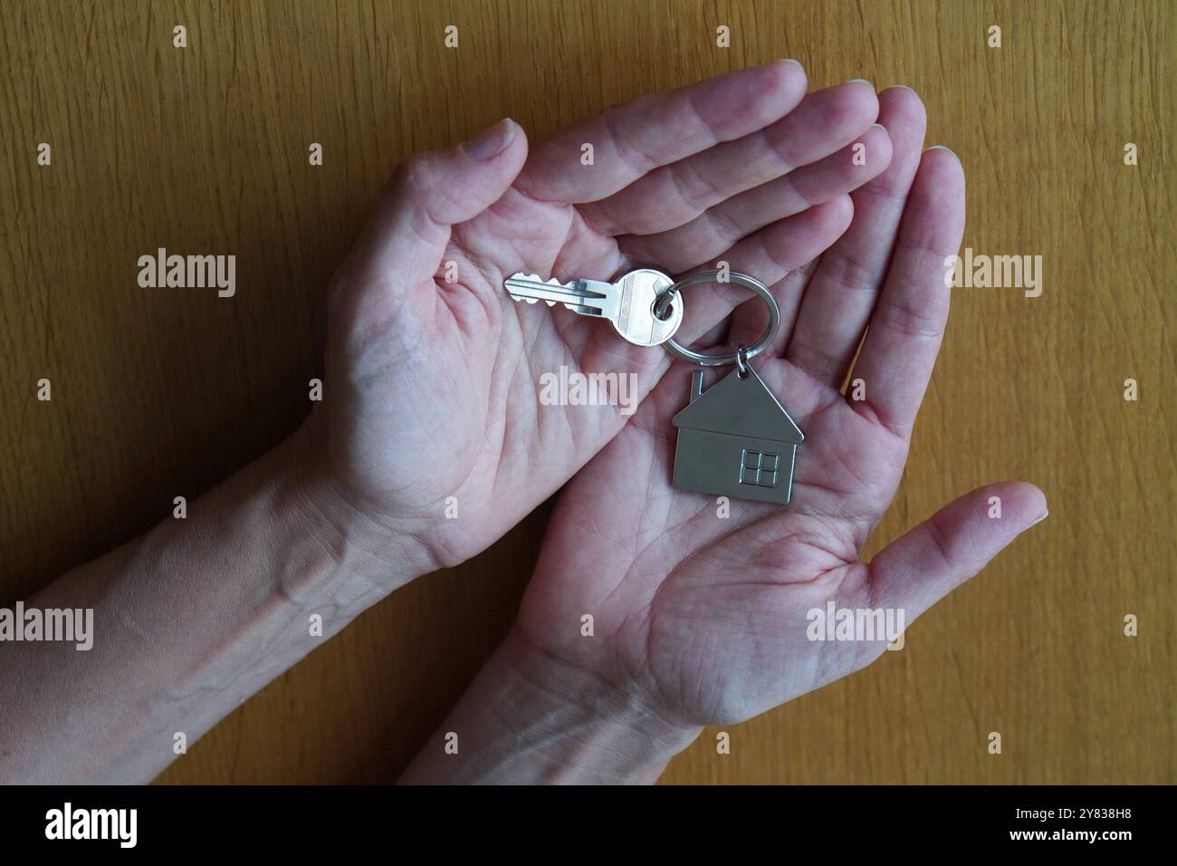 open hands with key and key ring of a house Stock Photo - Alamy
