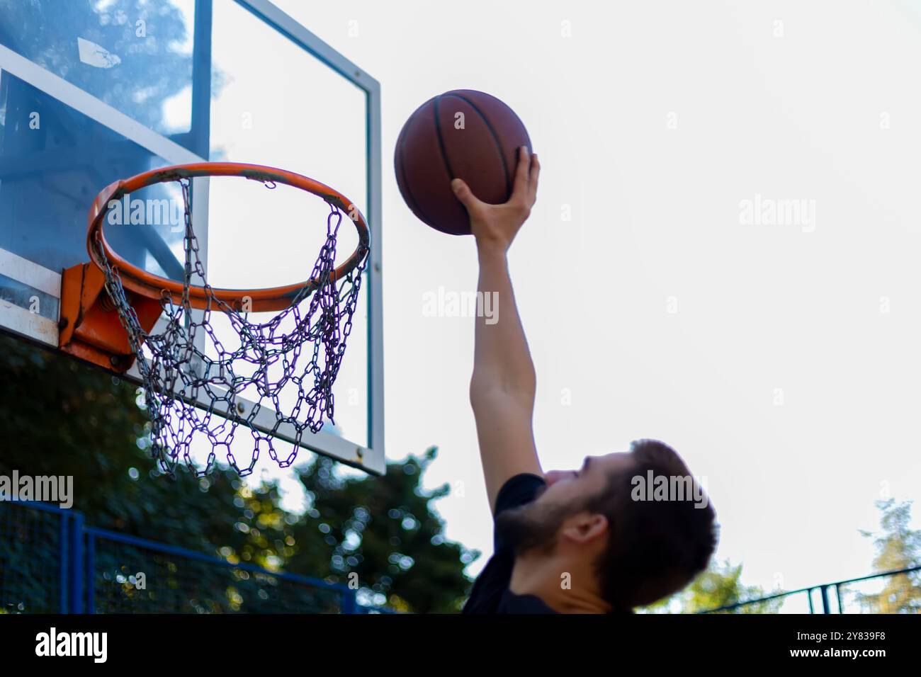 handsome basketball player shooting a ball through the hoop while ...