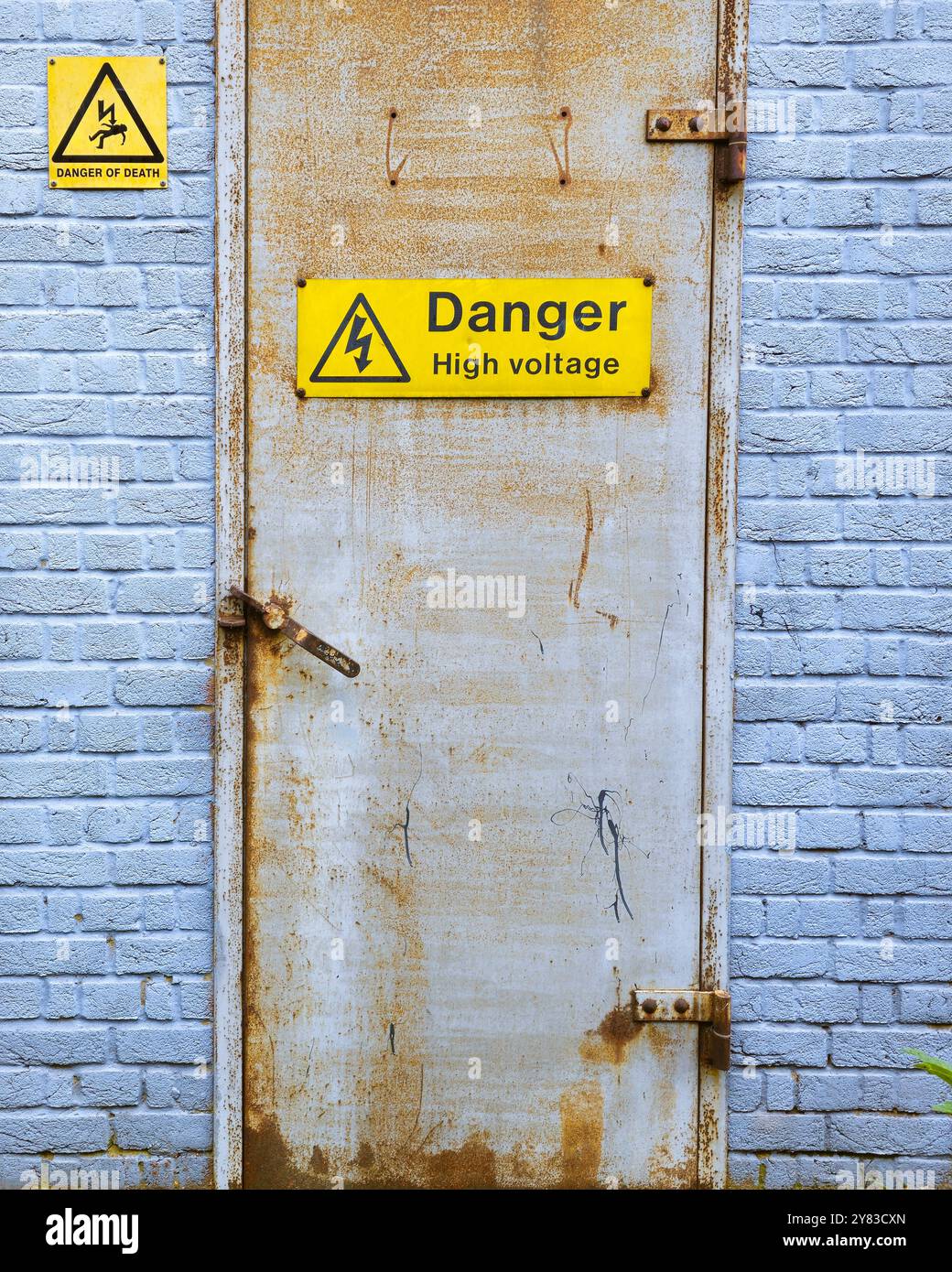 Rusty door with a high voltage danger sign, white bricks wall Stock ...