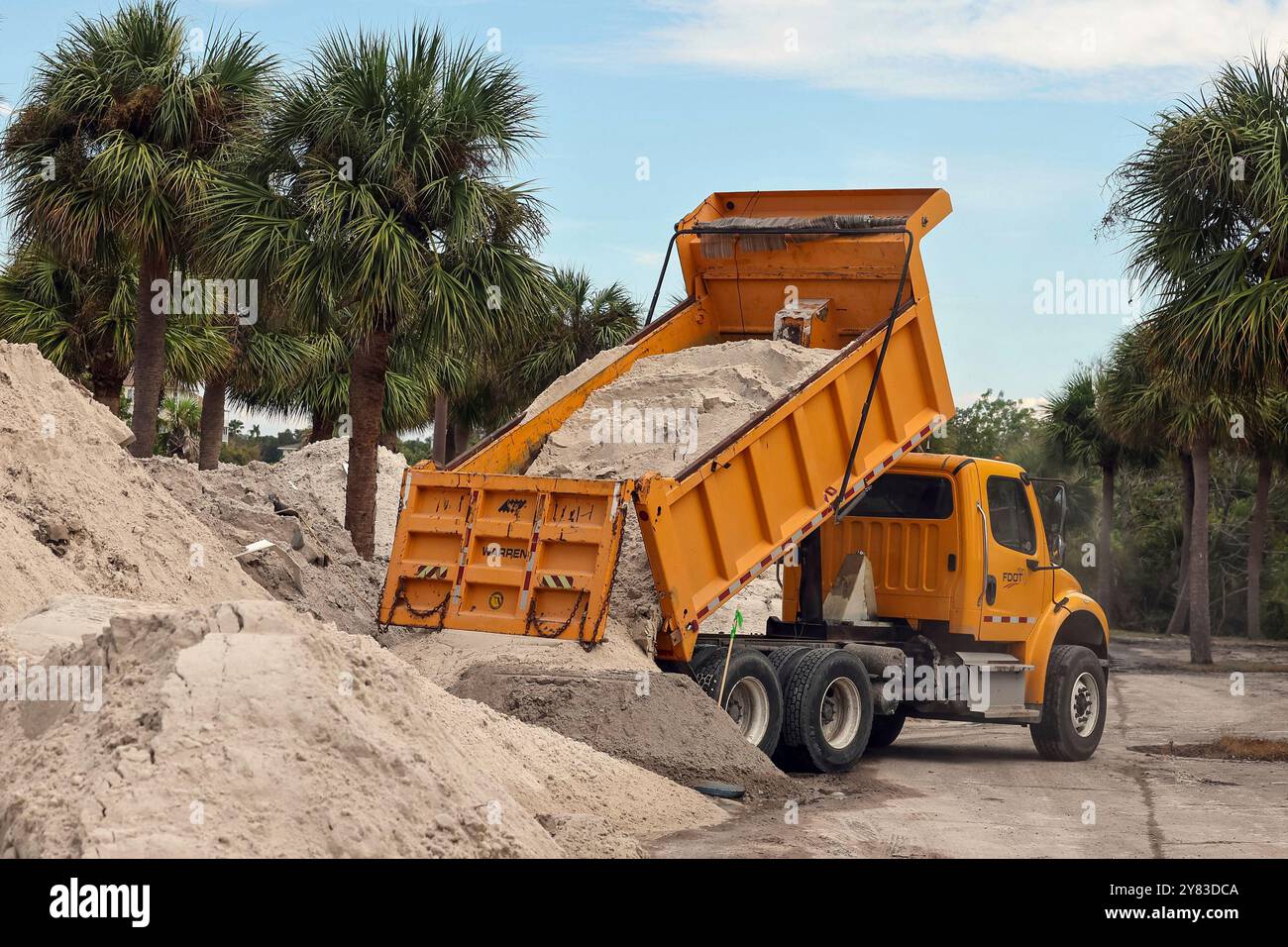 Crews dump sand that was cleared off of the streets from flooding from ...