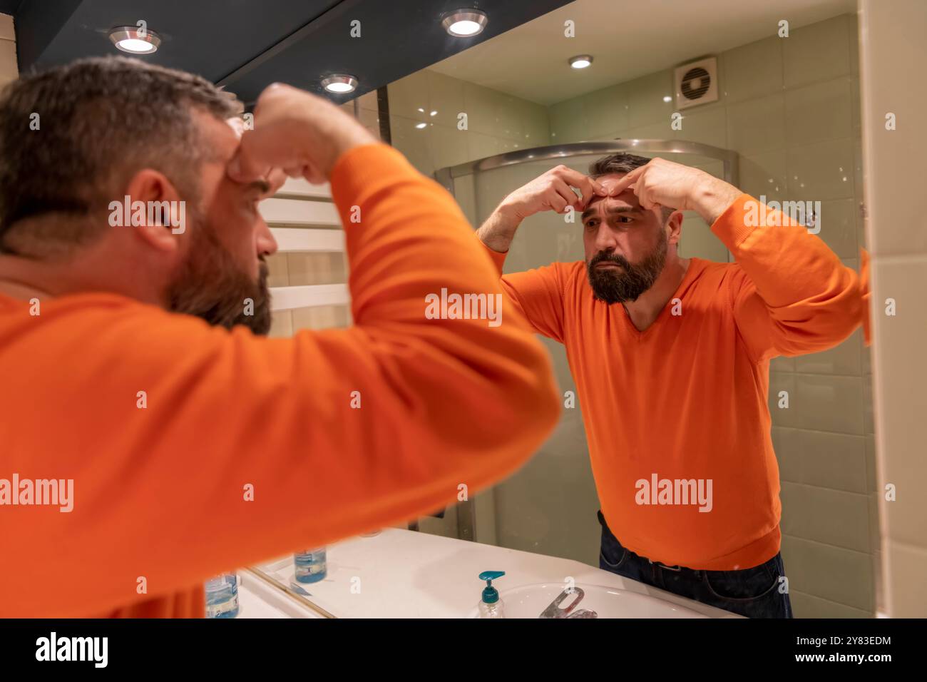 Adult man investigating his pimples on face. Guy trying to get rid of ...