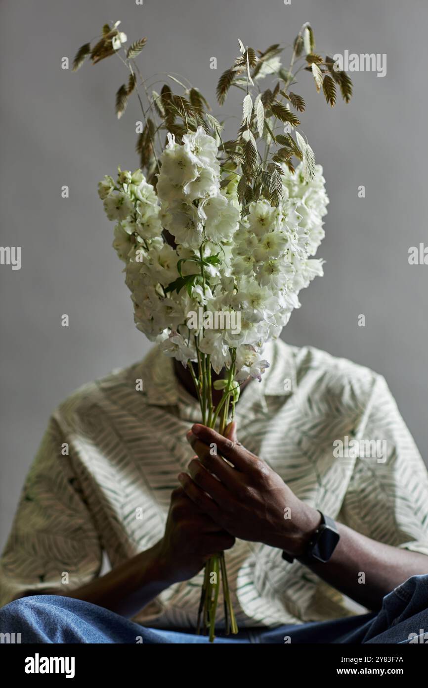 Minimal portrait of young African American man holding exotic flowers ...