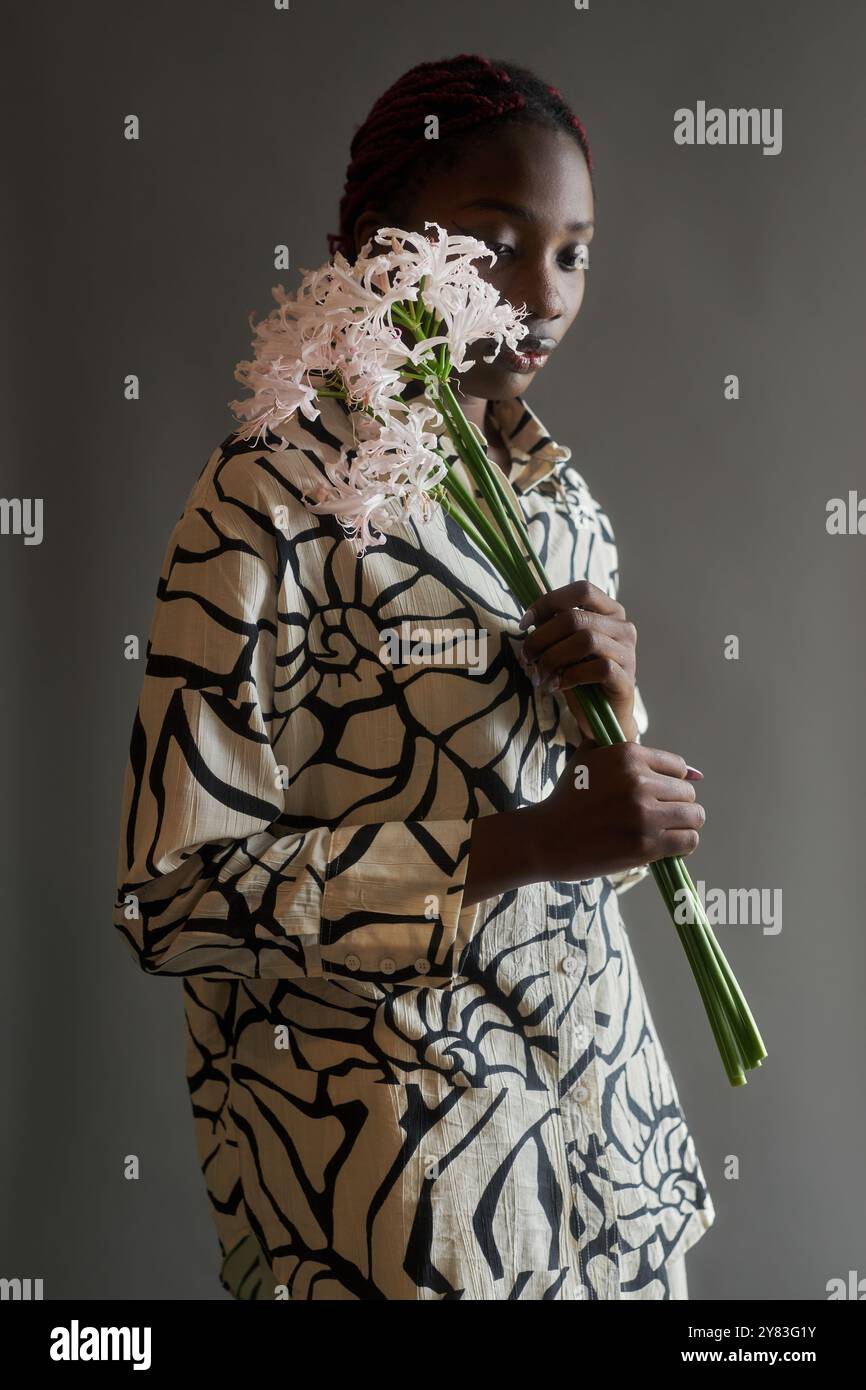 Delicate portrait of young Black woman posing with exotic flowers ...