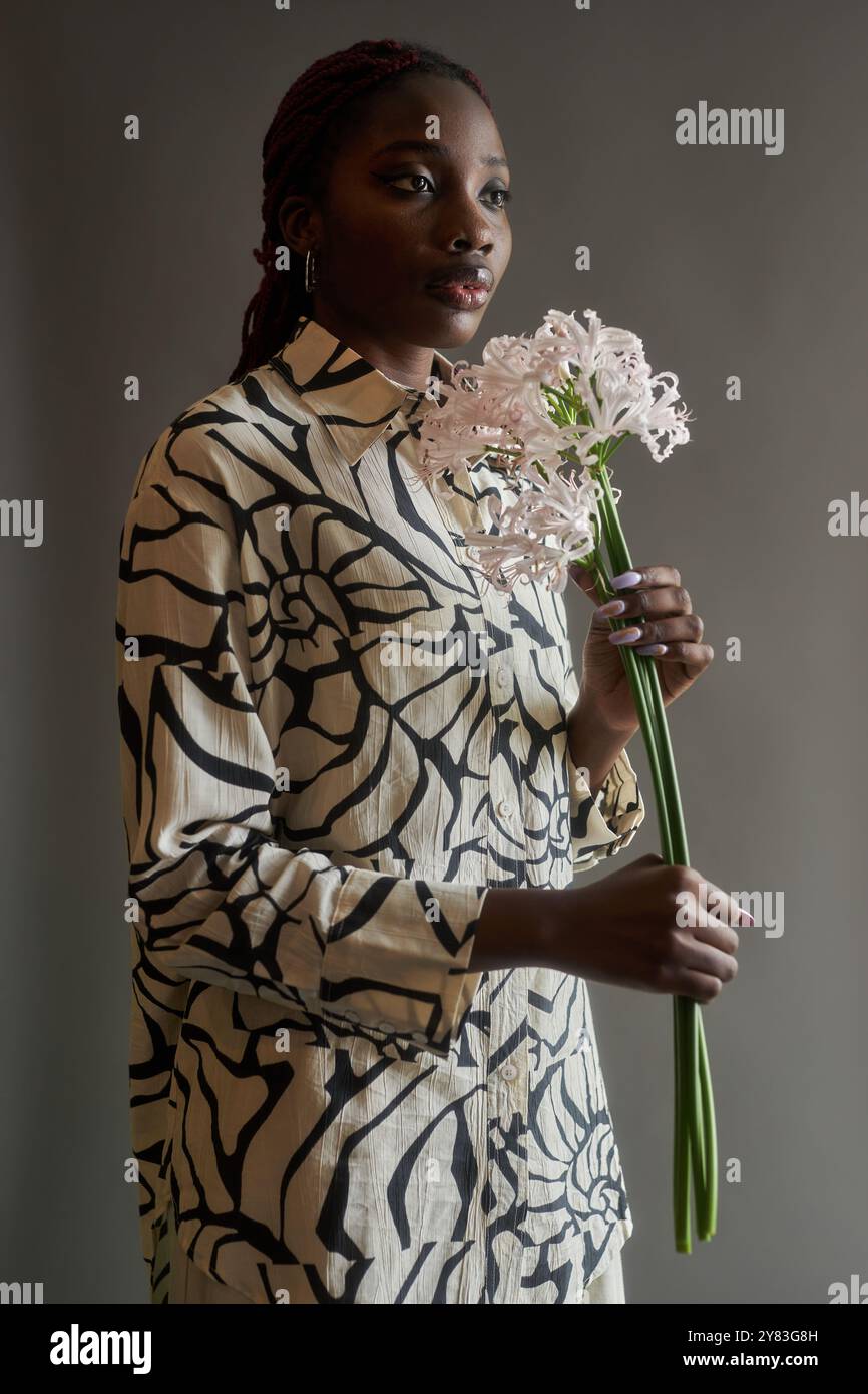 Delicate portrait of young Black woman posing with exotic blue flower ...