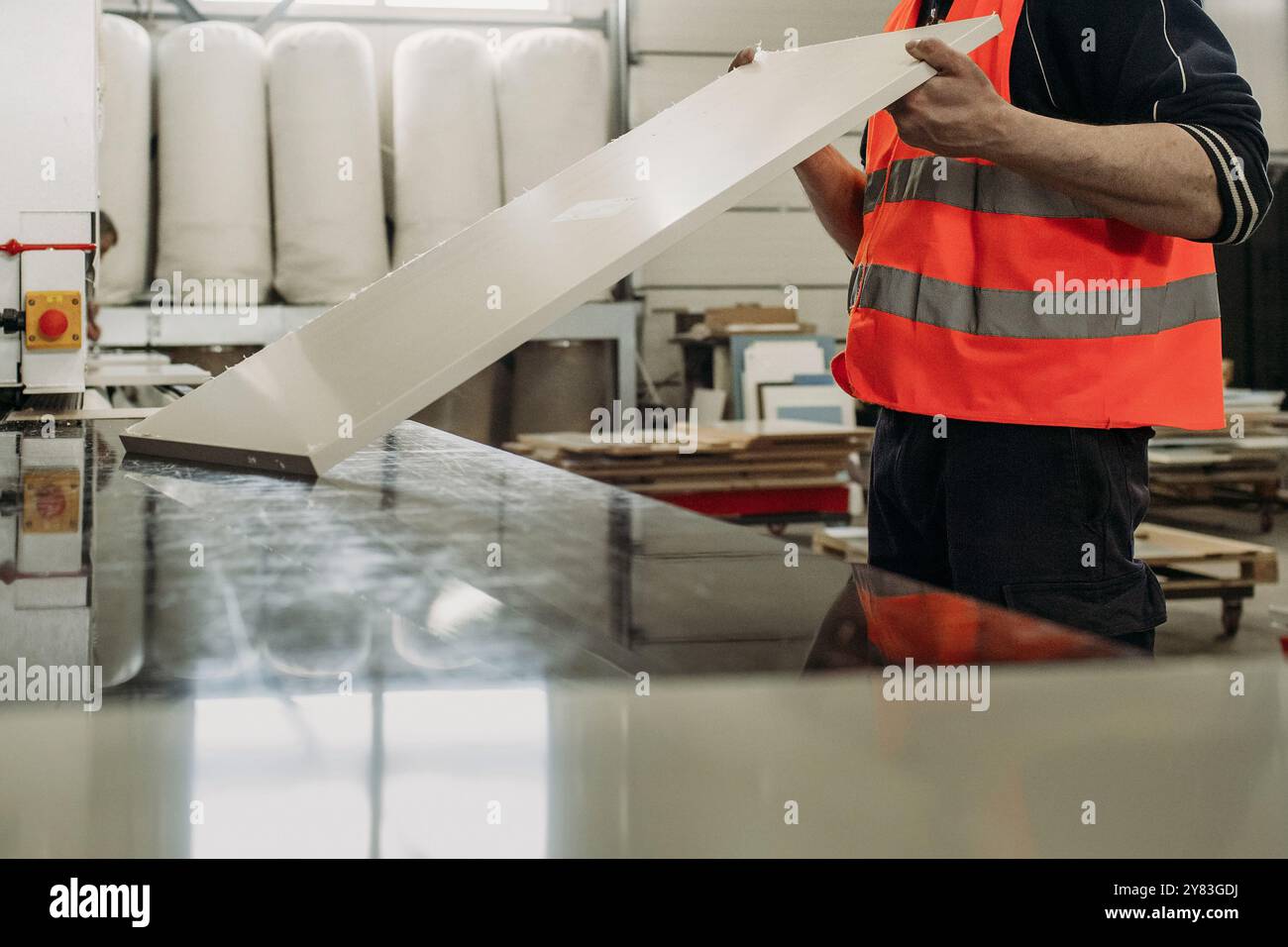 A diligent worker in high-visibility gear carefully handles a long ...