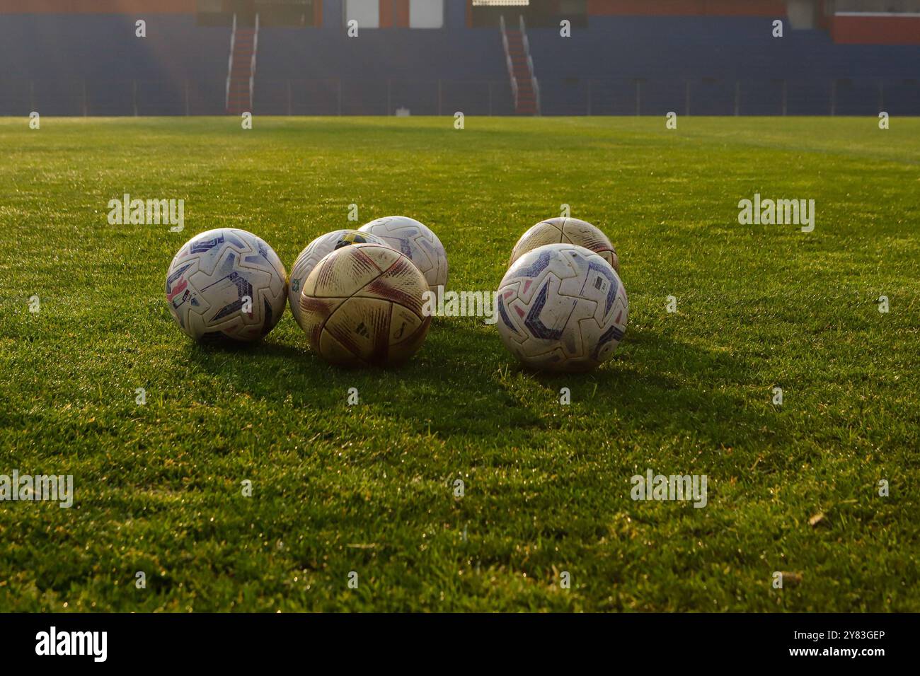 Balls on a soccer field on a green grass with hard light and orange ...