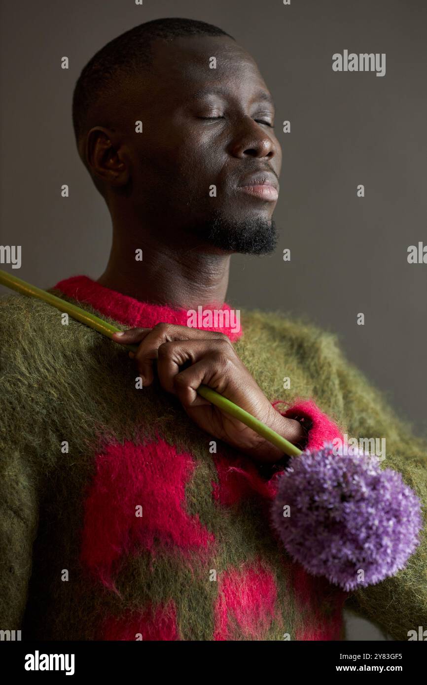 Side view fashion portrait of young African American man holding pink ...