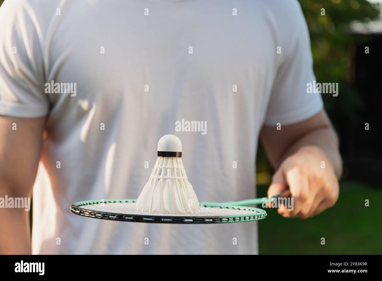 White badminton shuttlecock and badminton racket in man hands. Summer ...