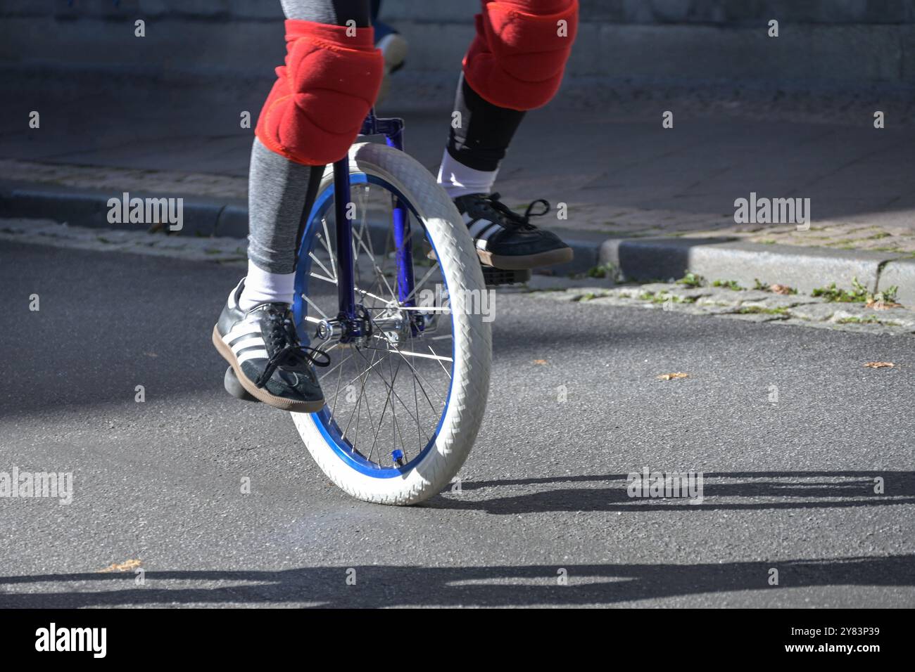 Legs with red knee pads riding a unicycle on a city street, the sport ...