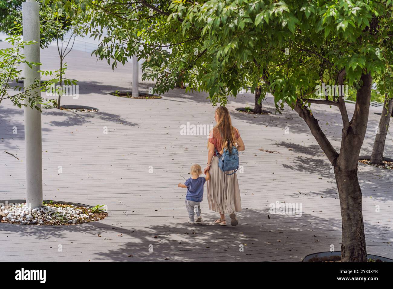 Mother with her toddler son walking in the park. Family bonding, outdoor exploration, and ...