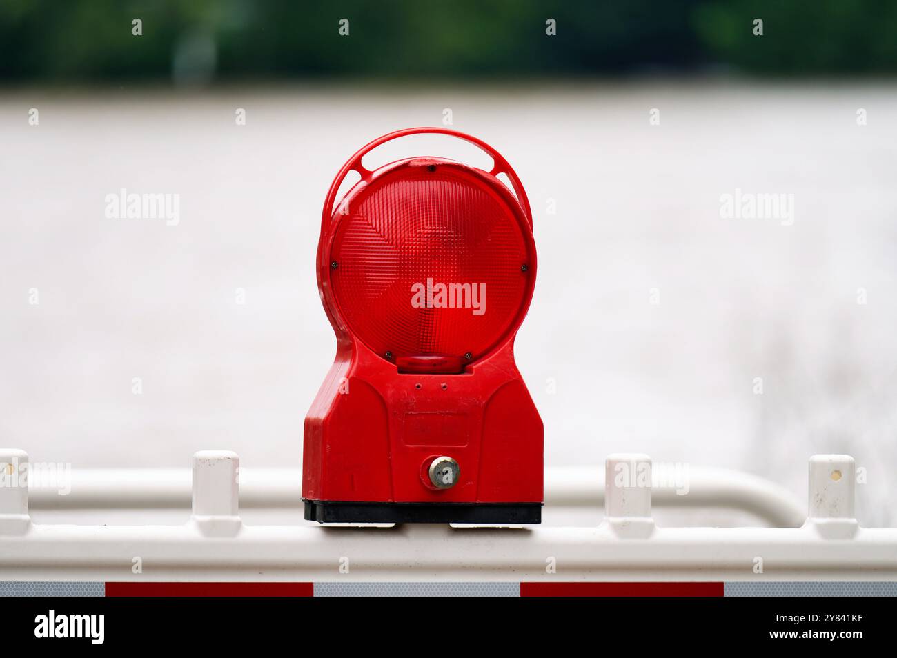 red warning light on a barrier fence with flooded water surface in a ...