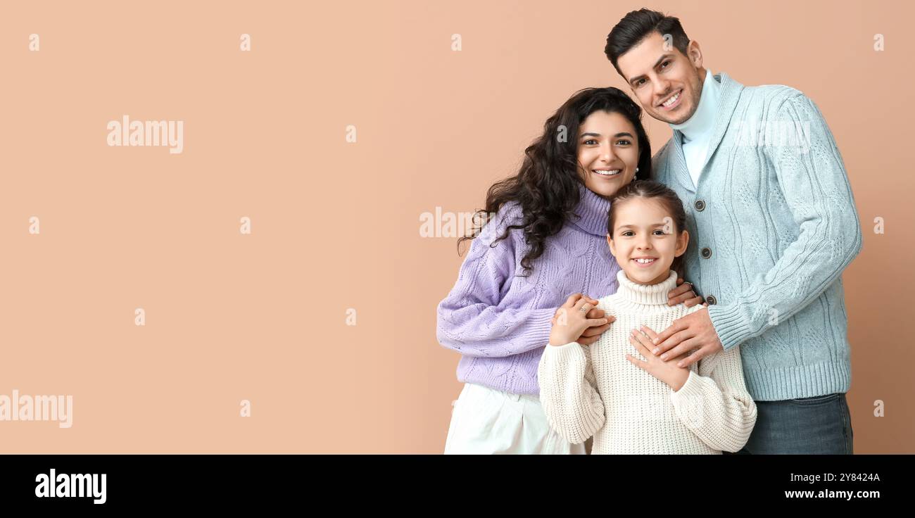 Little girl and her parents in warm sweaters on beige background with ...