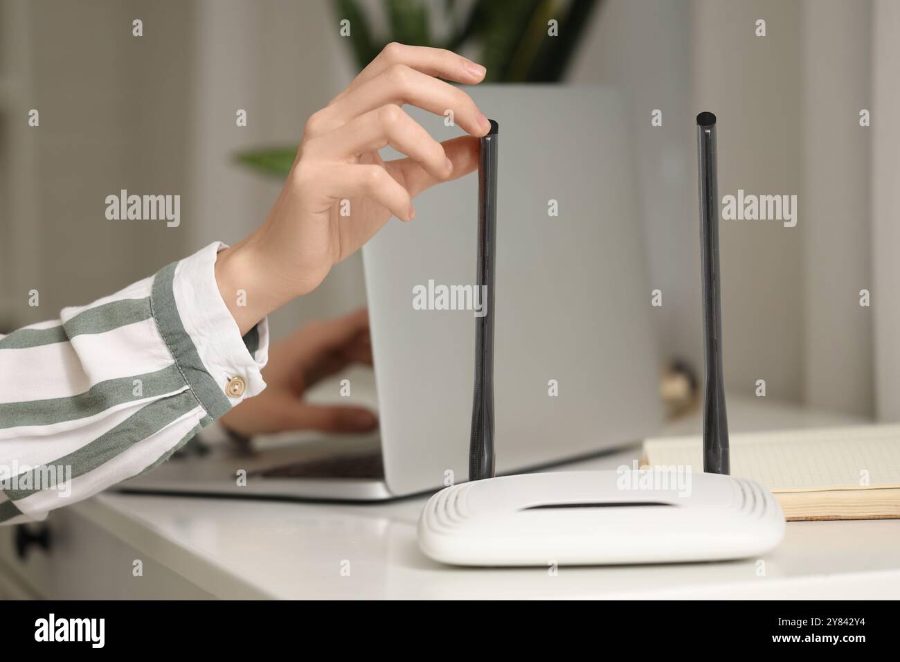 Modern wi-fi router on table of working woman with laptop, closeup ...