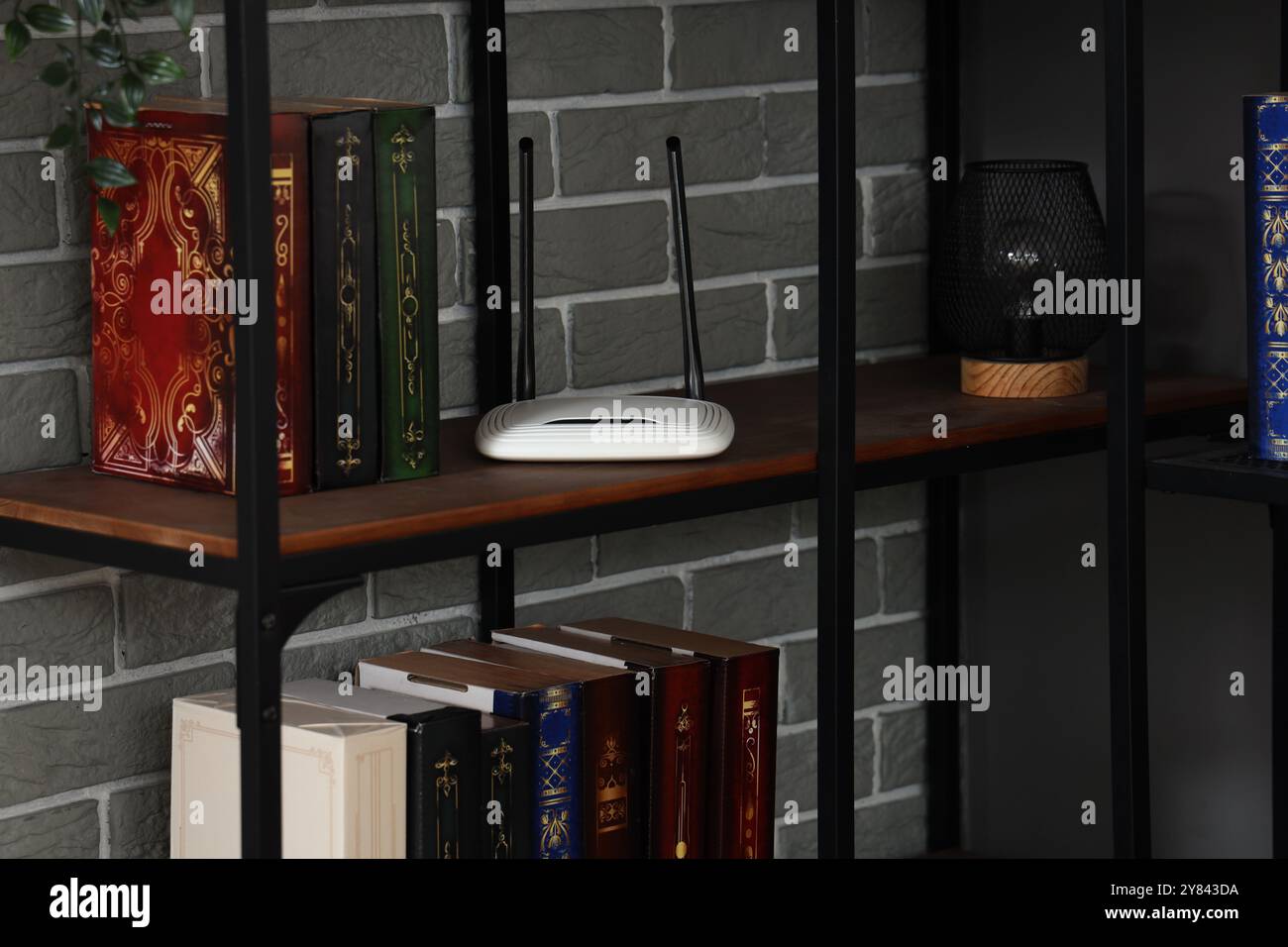 Modern wi-fi router on bookshelf in dark room Stock Photo - Alamy