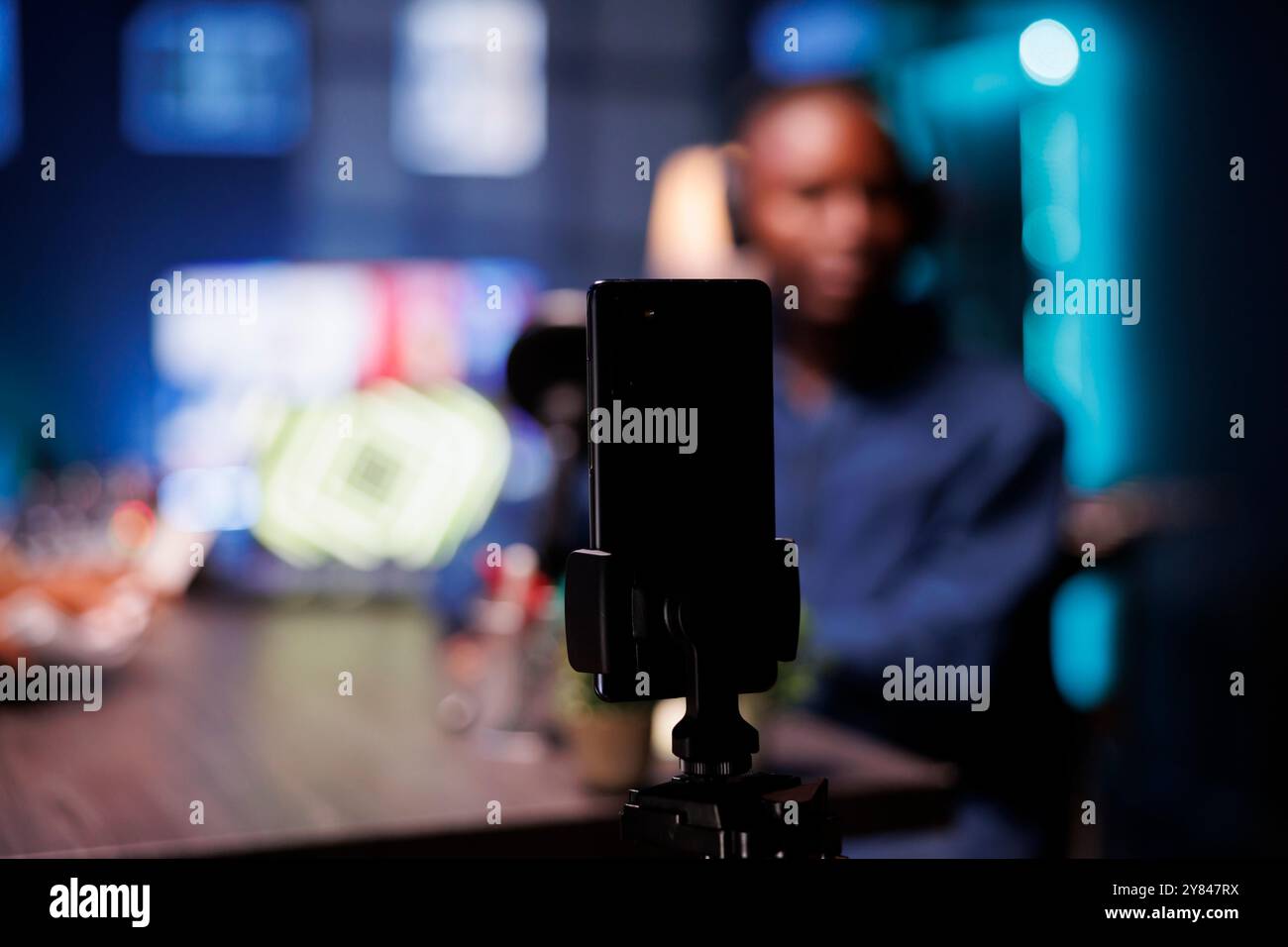 Focus on smartphone on tripod recording vlogger show host in blurry ...