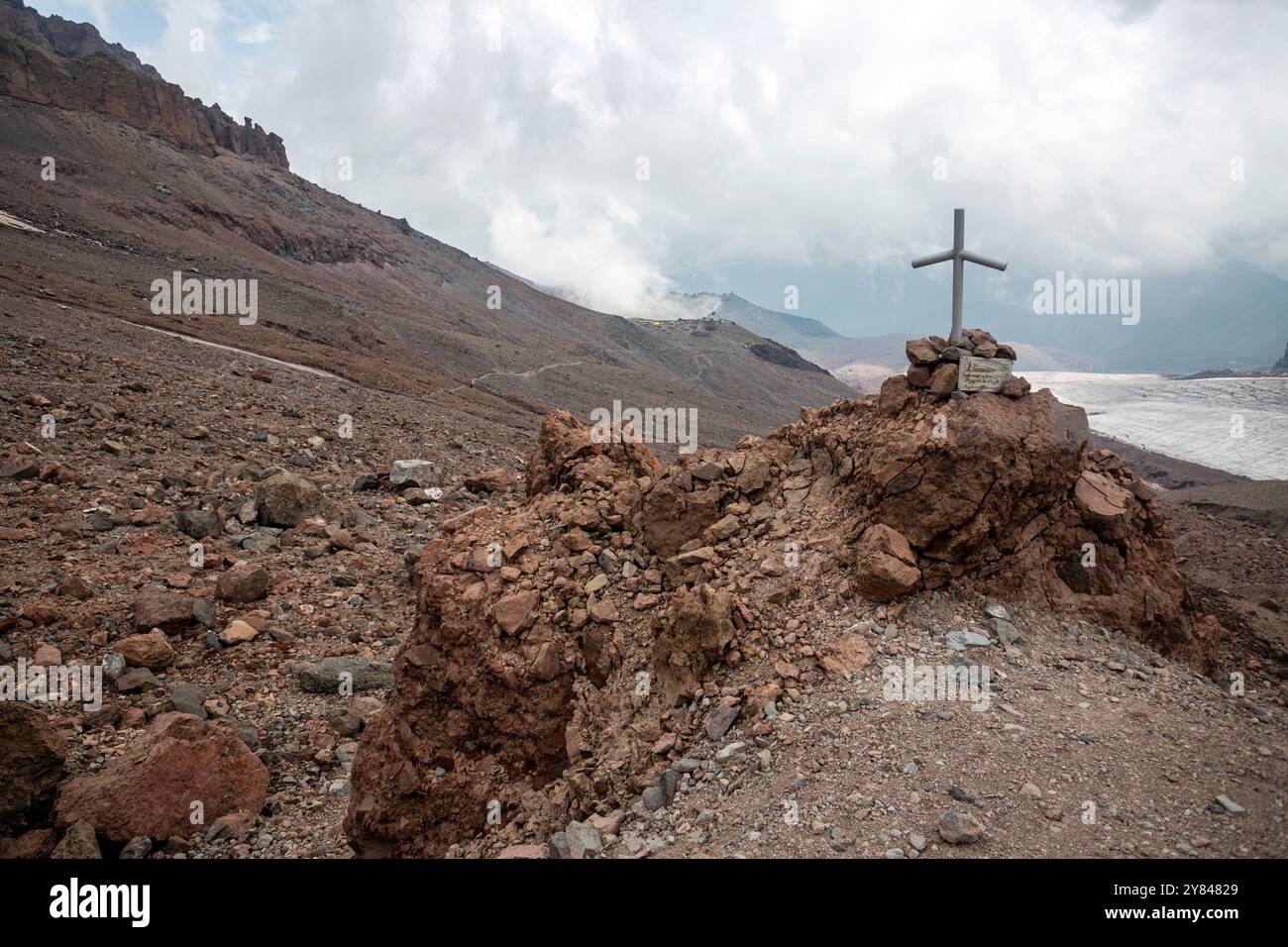 A winding path leads up a steep mountain. A solitary cross stands on a ...