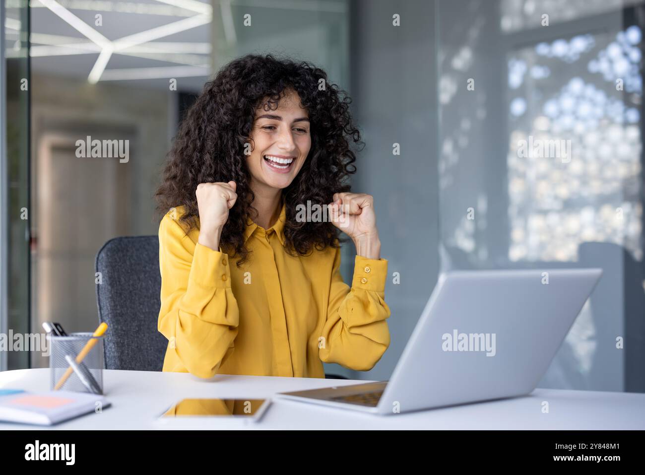 Hispanic businesswoman expresses excitement and success sitting at ...