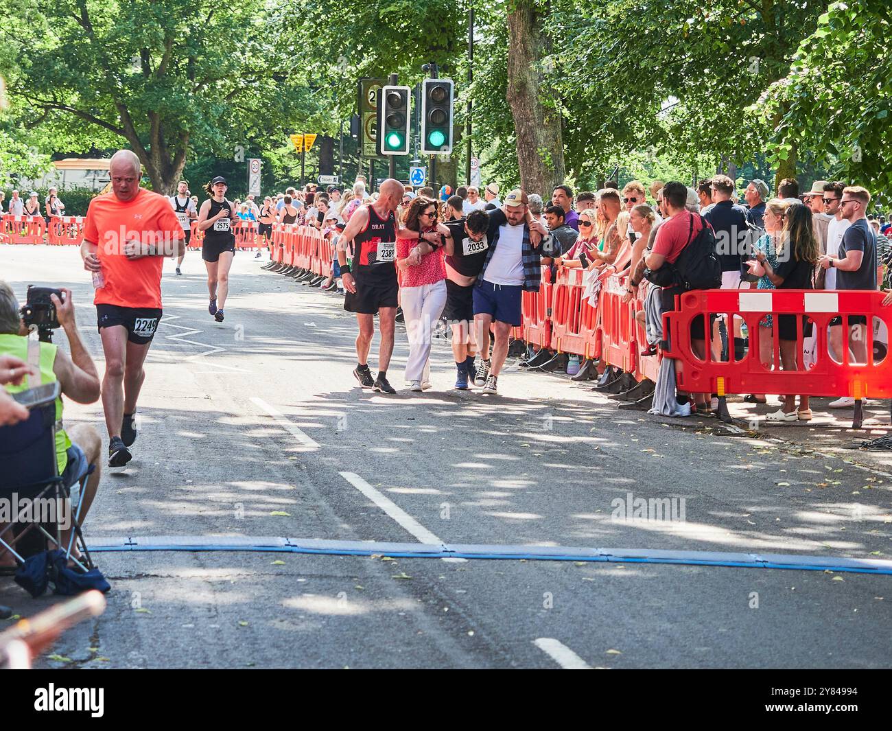 Exhausted half-marathon male runner being carried to the finish line ...