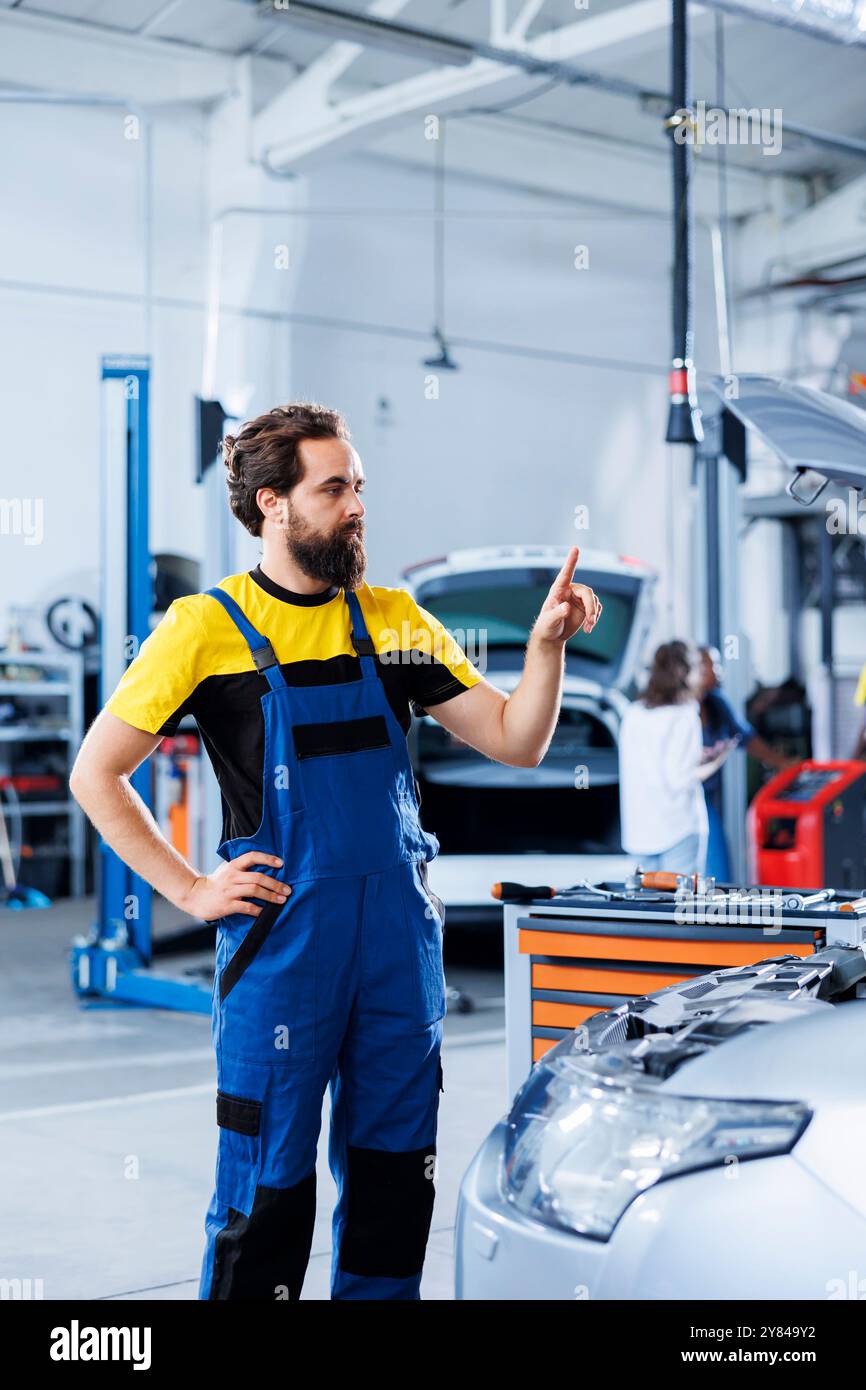 Repairman in repair shop using augmented reality holograms to check car ...