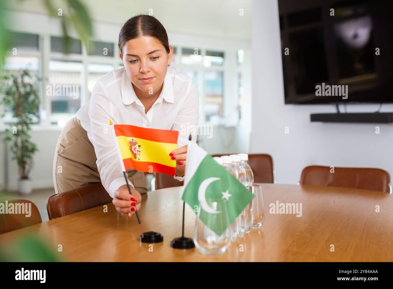 Positive young woman putting little flag of Spain on table next to the ...