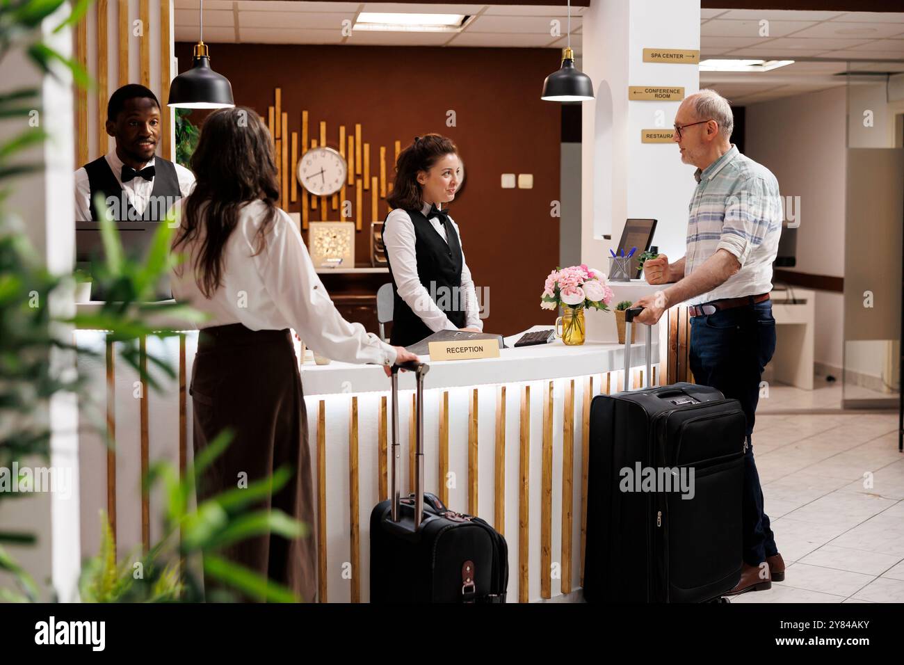 Helpful multiethnic receptionists assisting elderly guests at the front ...