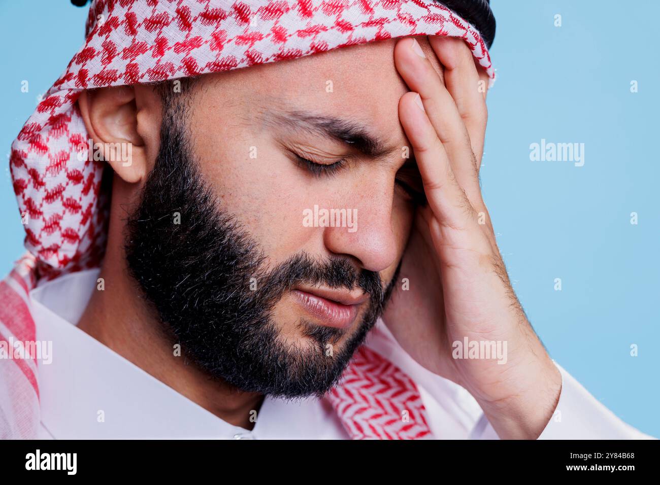 Arab man with exhausted expression holding forehead while suffering ...